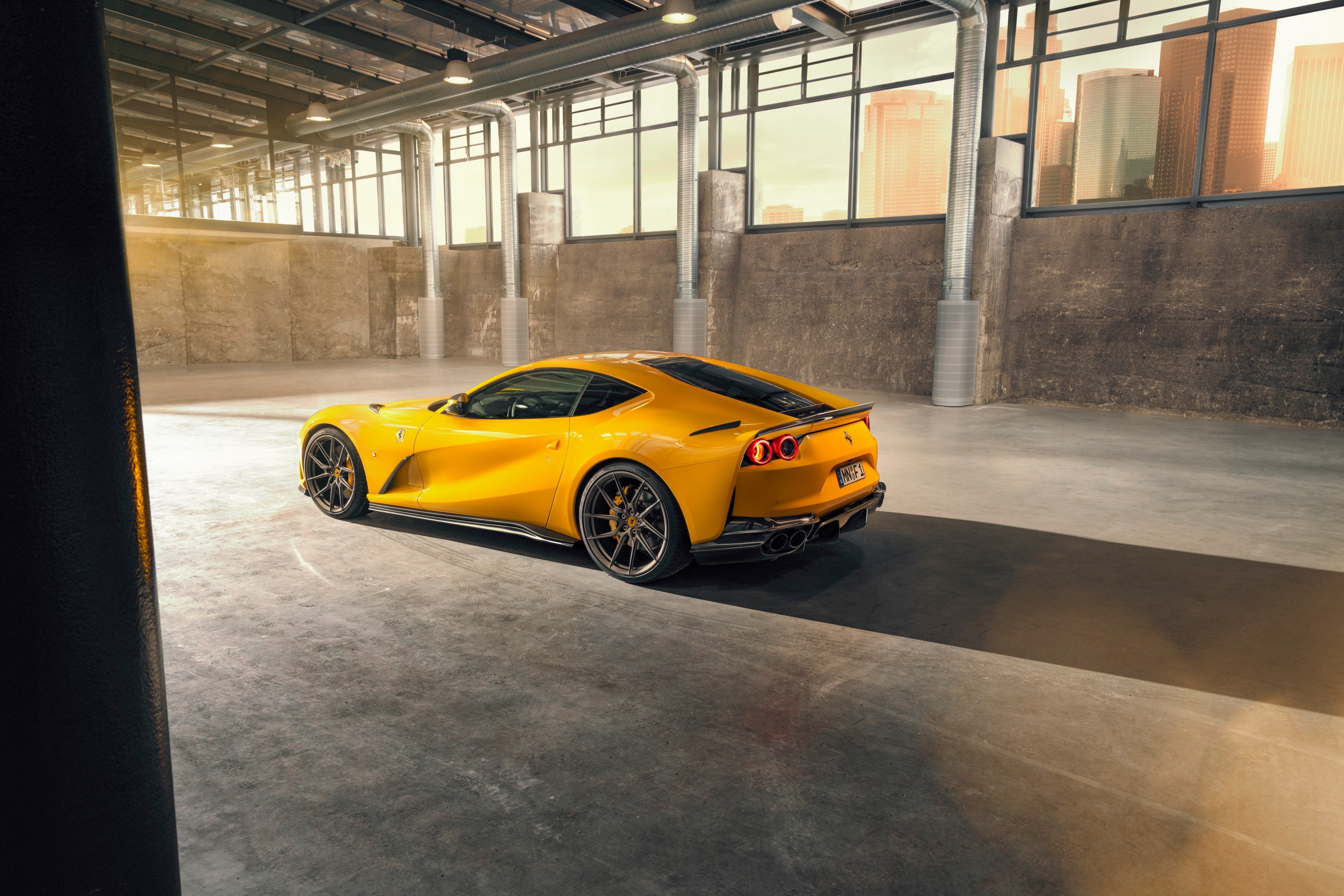 Yellow ferrari 812 superfast standing in a hangar with large windows ...